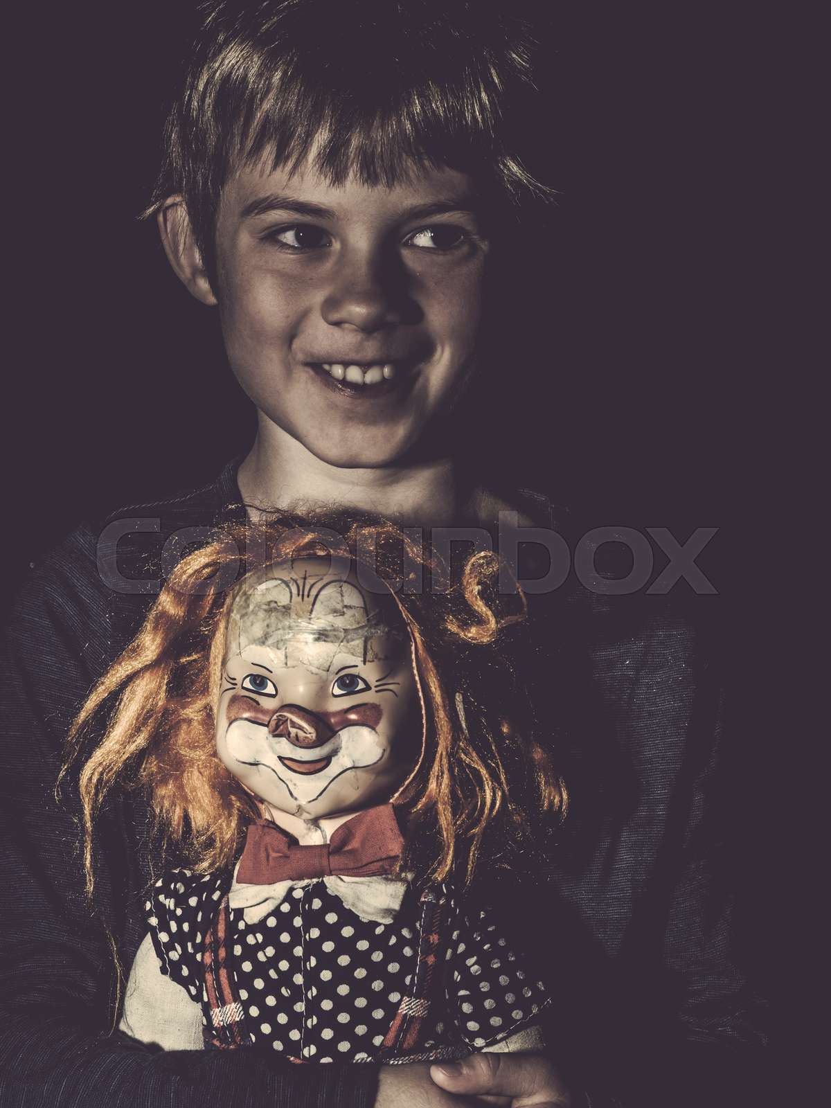 Creepy young boy with scary doll | Stock image | Colourbox