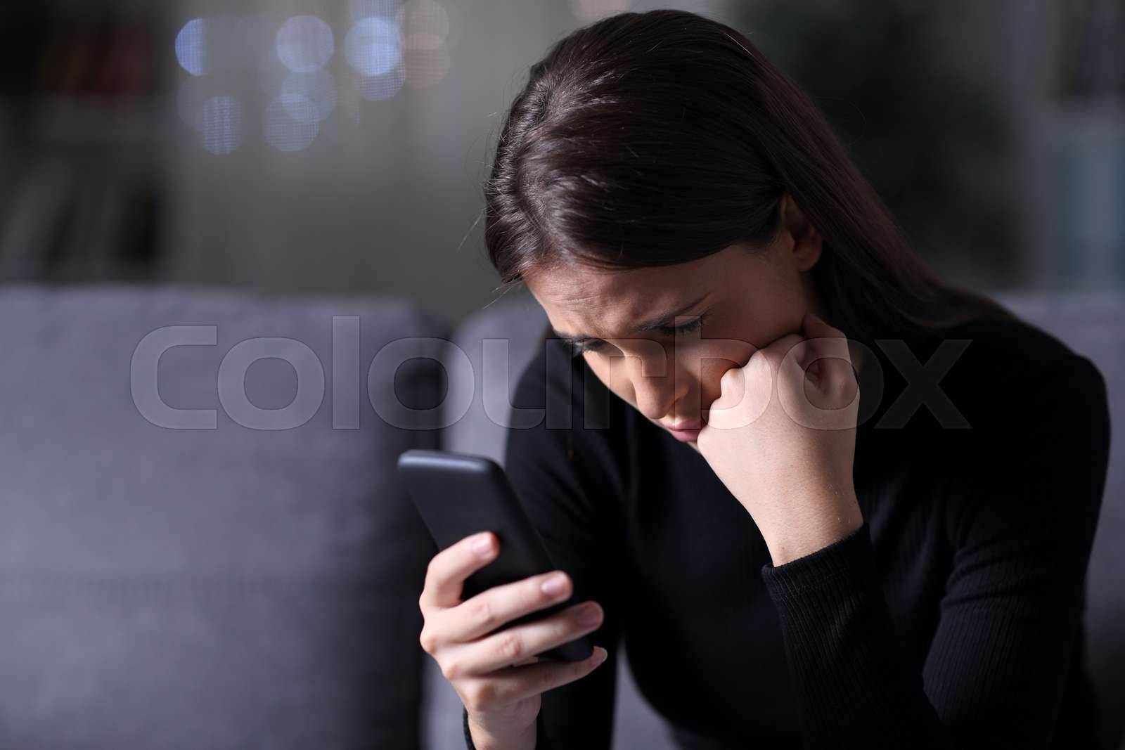 Worried girl reading phone message in the night | Stock image | Colourbox