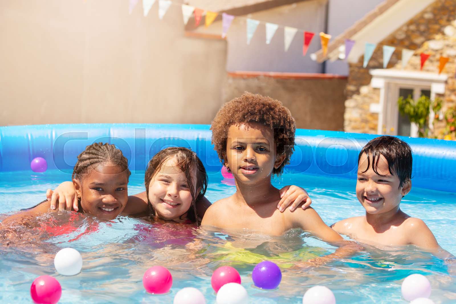 Four happy children hug sit smile in swim pool | Stock image | Colourbox