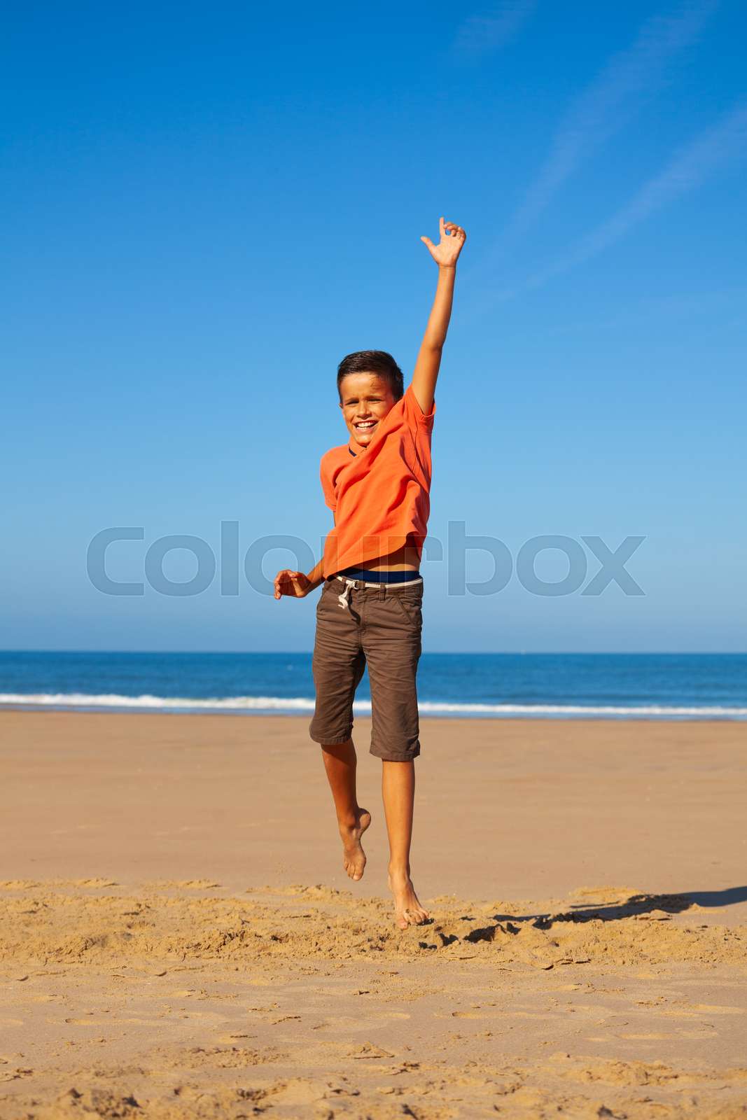 Handsome boy in red shirt jump lifting hand | Stock image | Colourbox