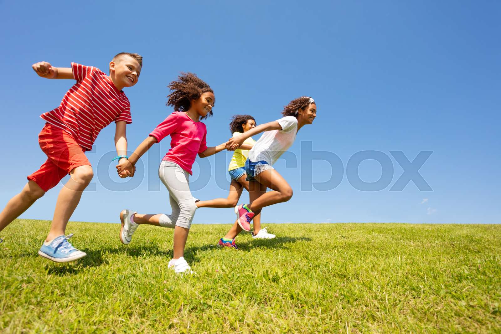 Diverse group of happy kids run in park hold hands | Stock image ...