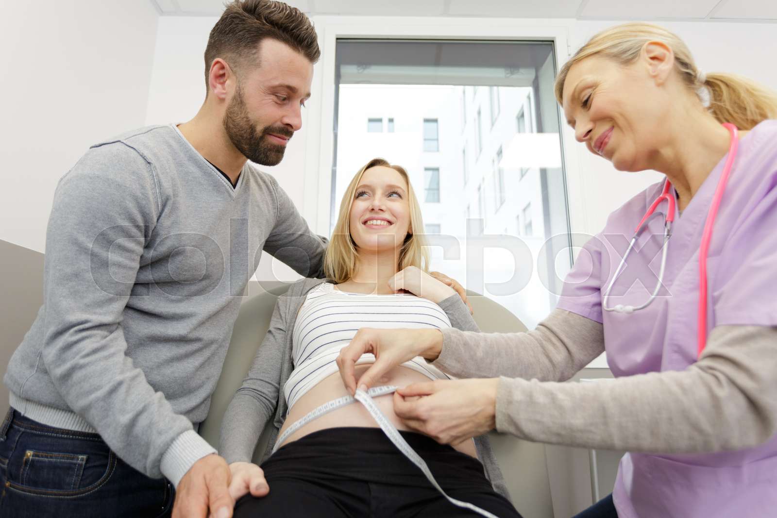 positive gynecologist taking measurement of baby bump | Stock image ...