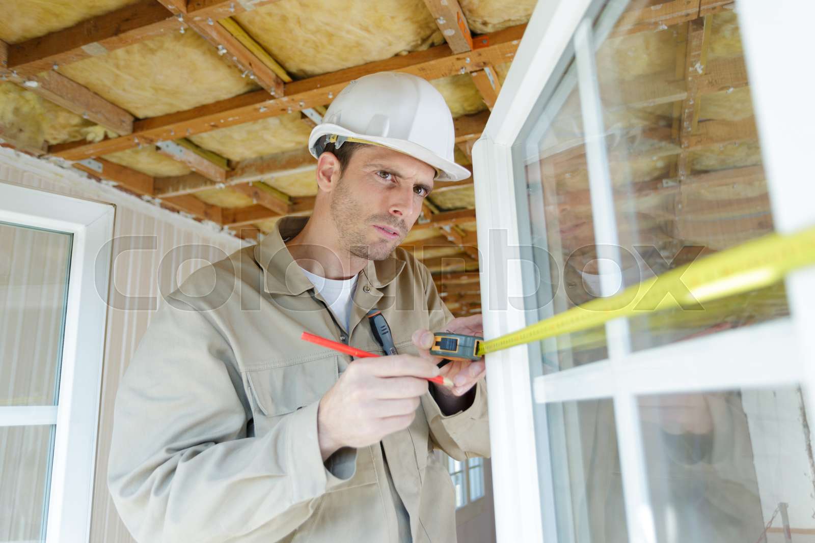 a workman measuring a window | Stock image | Colourbox