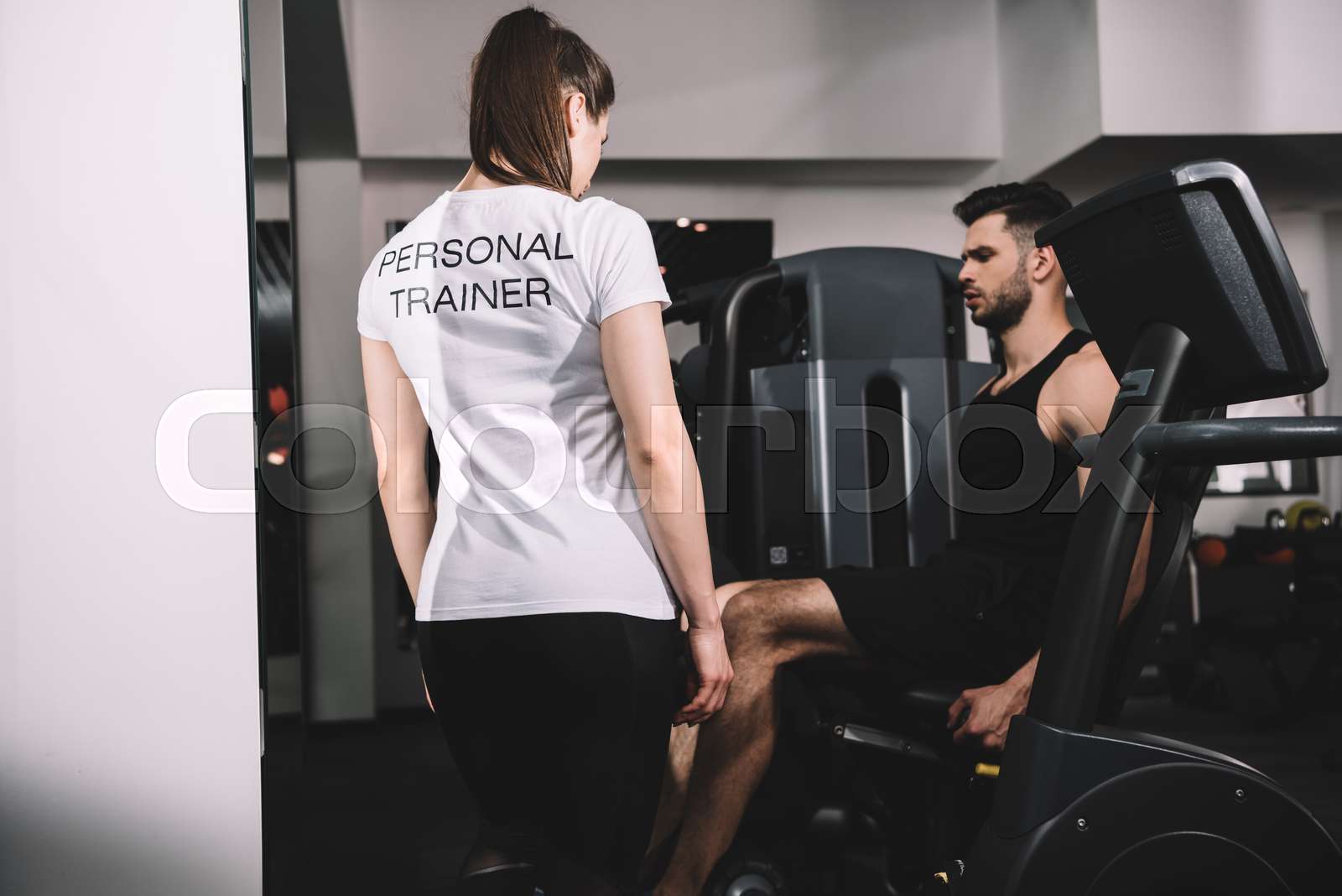 back view of personal trainer instructing handsome sportsman working ...