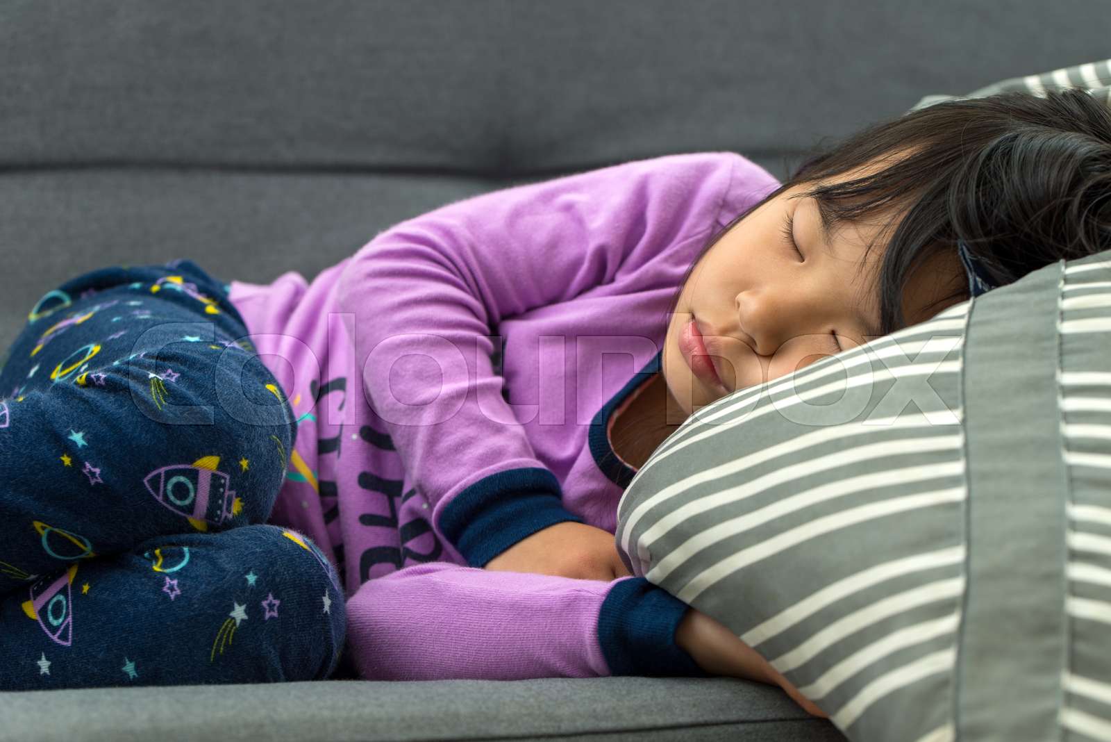 Little Asian child taking nap on couch | Stock image | Colourbox