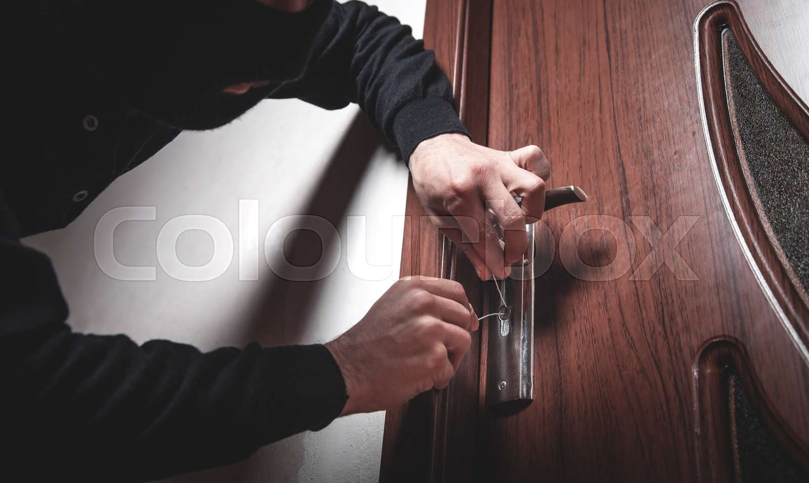 Robber with black mask trying to open door. | Stock image | Colourbox