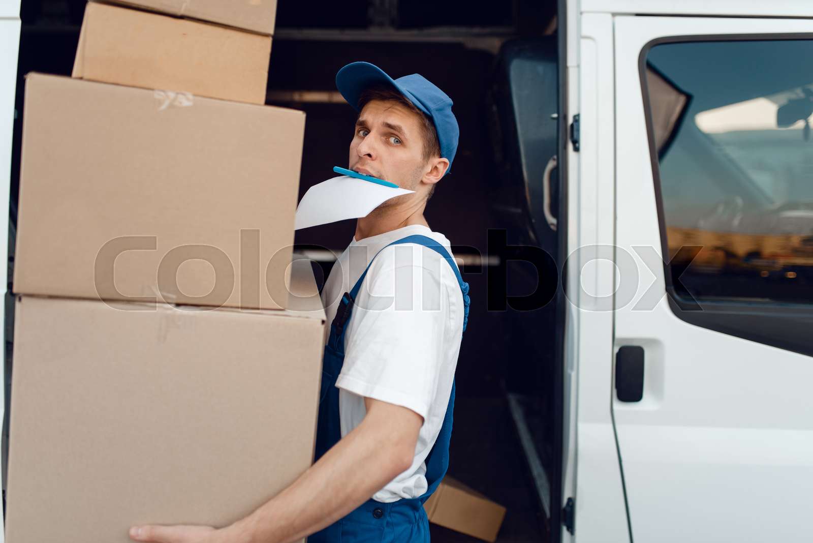 Loader holding stack of parcels, delivery service | Stock image | Colourbox