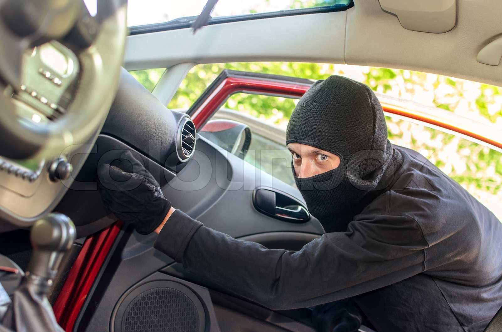 Thief in the mask breaks the door in a vehicle | Stock image | Colourbox