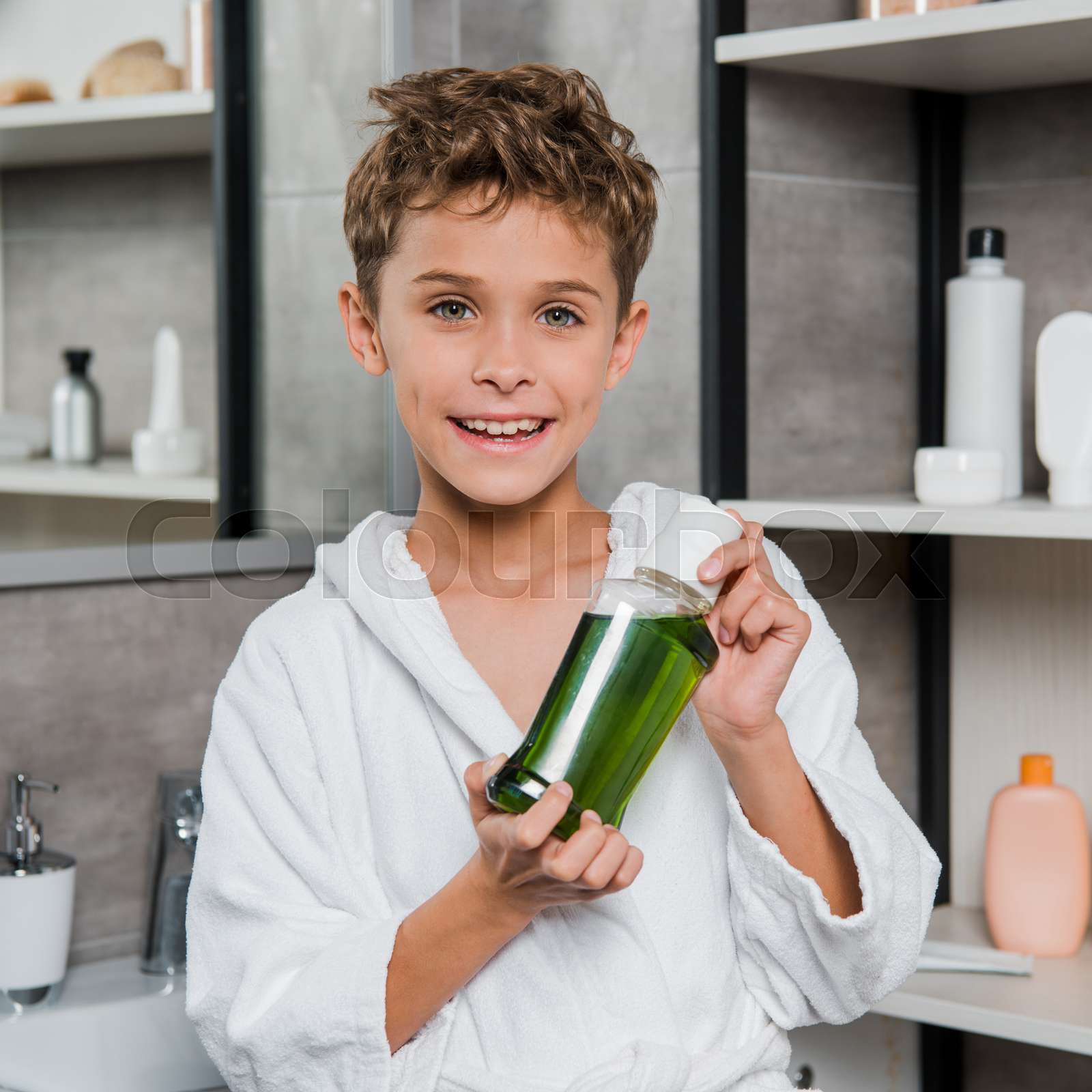 cheerful boy holding bottle with green mouthwash in bathroom | Stock ...