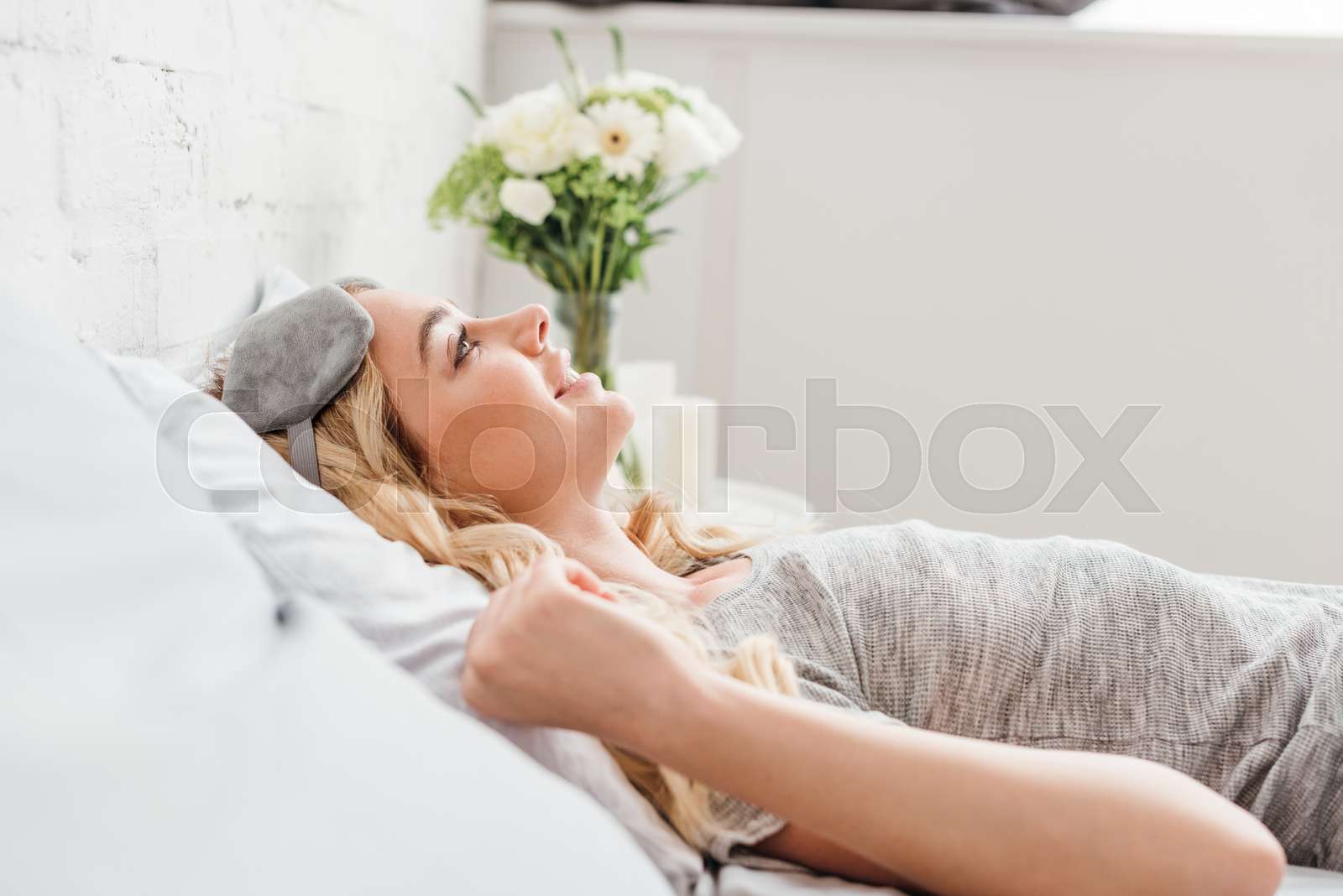 side view of happy girl with eye mask lying on bed | Stock image ...