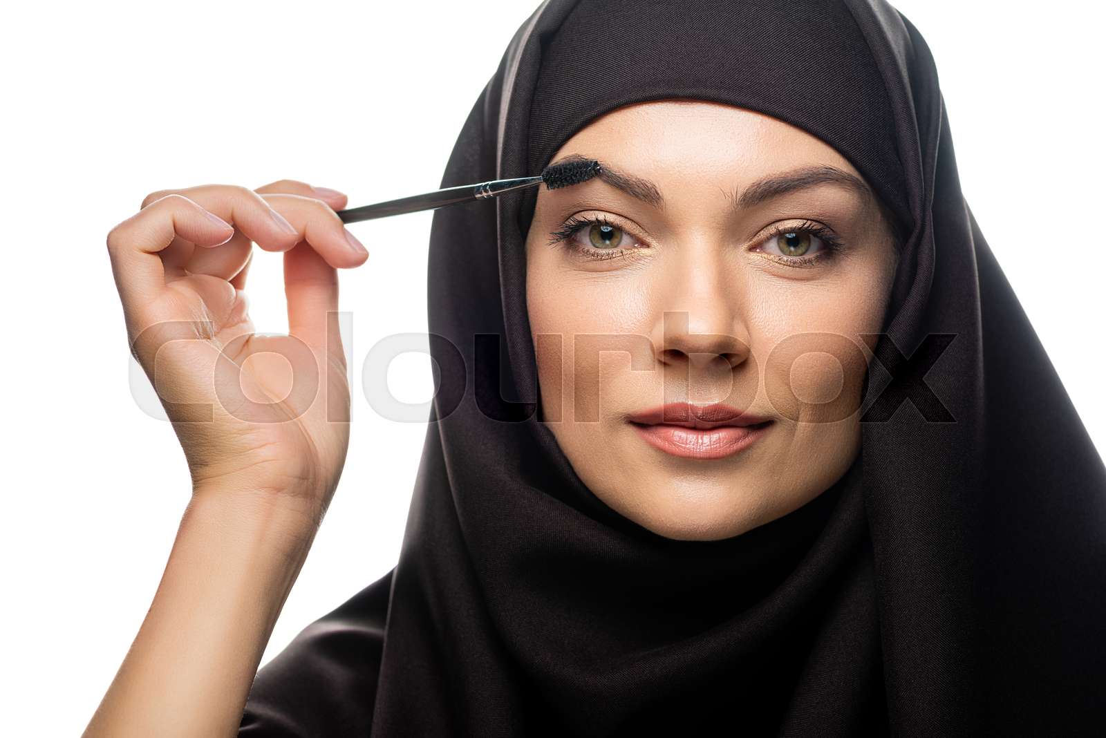 young Muslim woman in hijab applying mascara on eyelashes isolated on ...