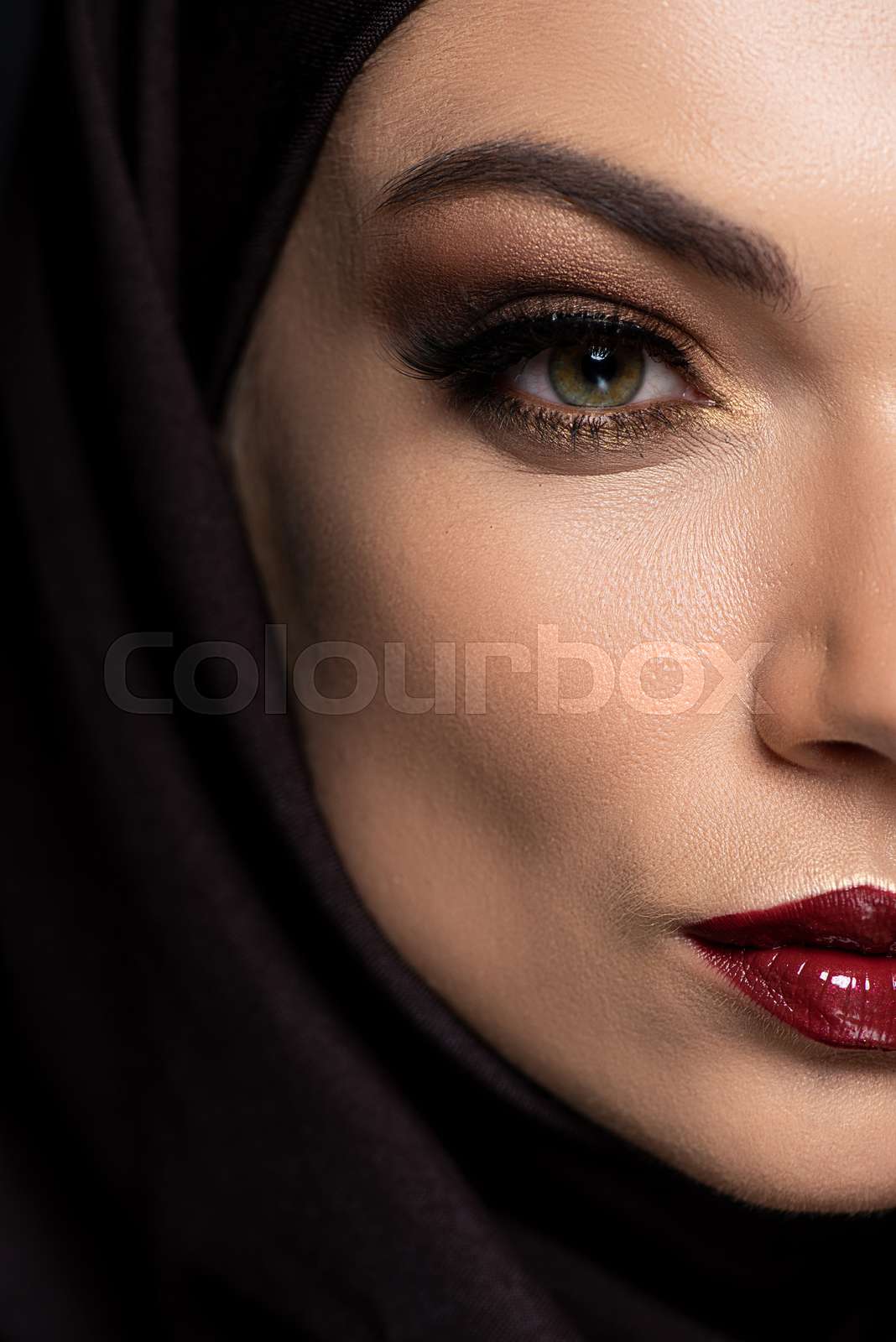 close up view of young Muslim woman in hijab with smoky eyes and red ...
