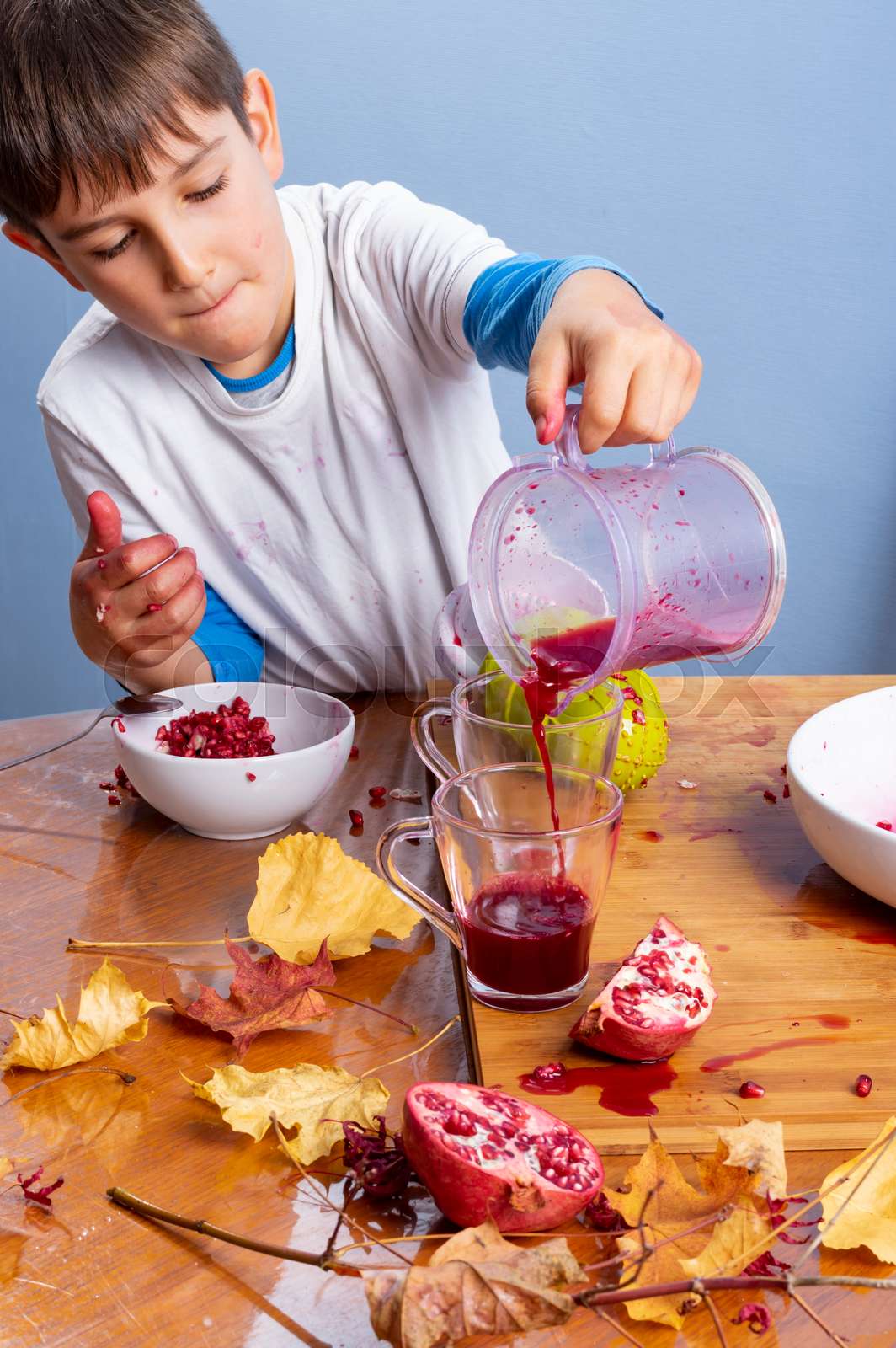 Young boy squeezing and pouring pomegranate juice, making a mess. Face ...