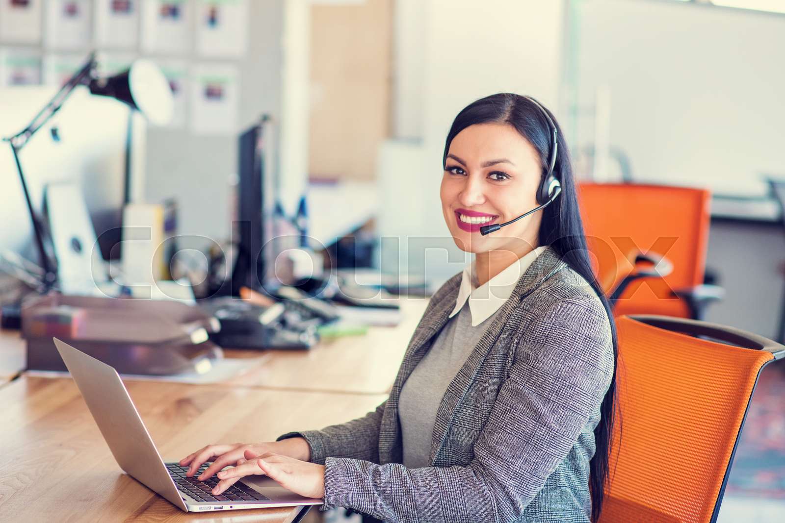 Beautiful call center agent browsing the internet on her computer ...