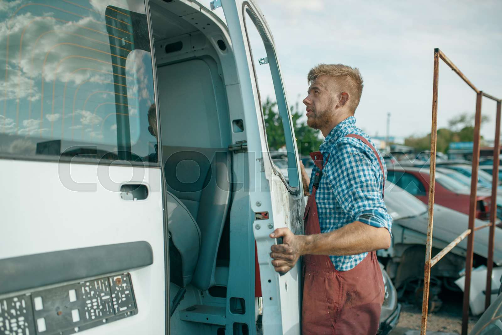 Male repairman removes the door on car scrapyard | Stock image | Colourbox