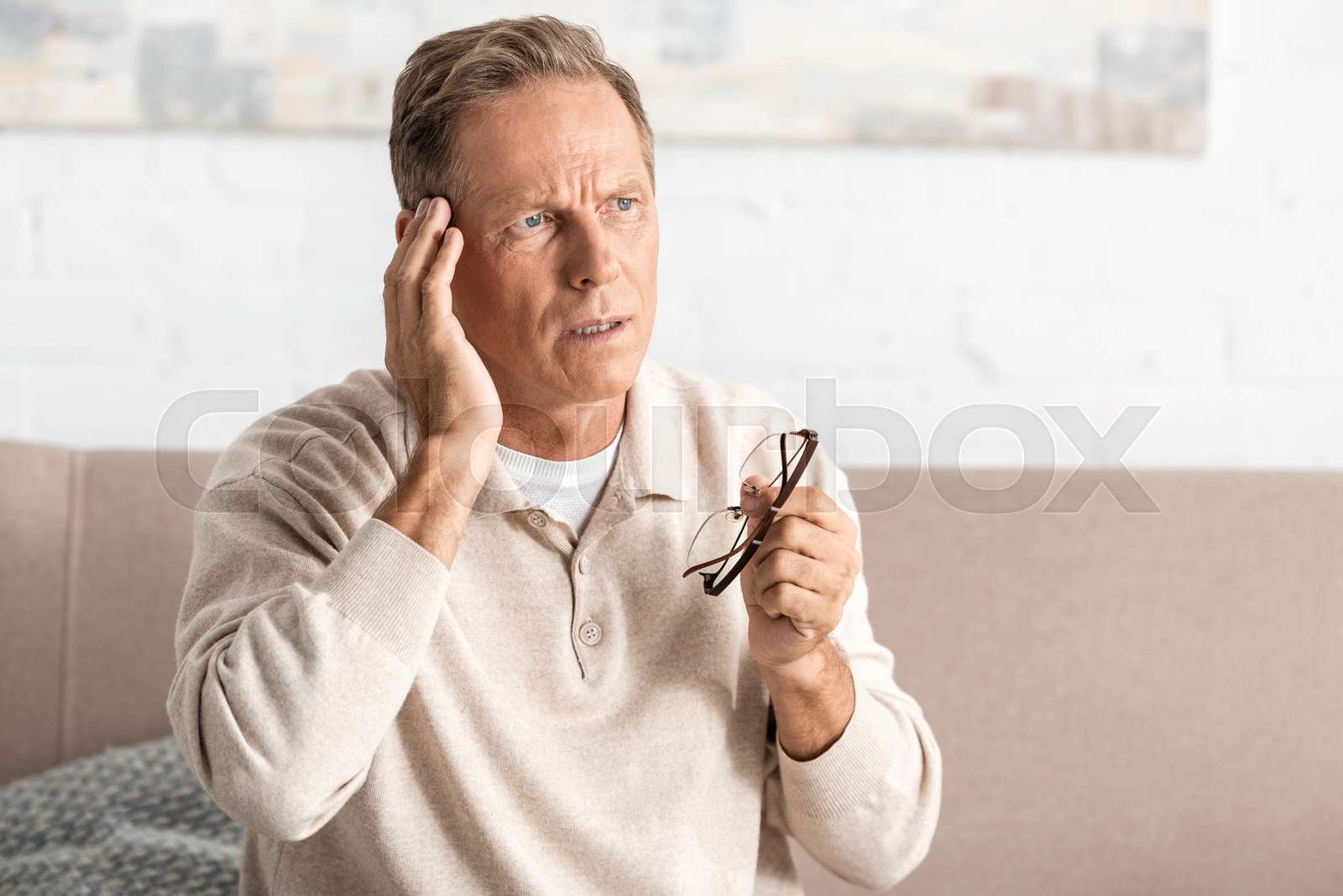 thoughtful senior man with memory loss touching temple while holding ...
