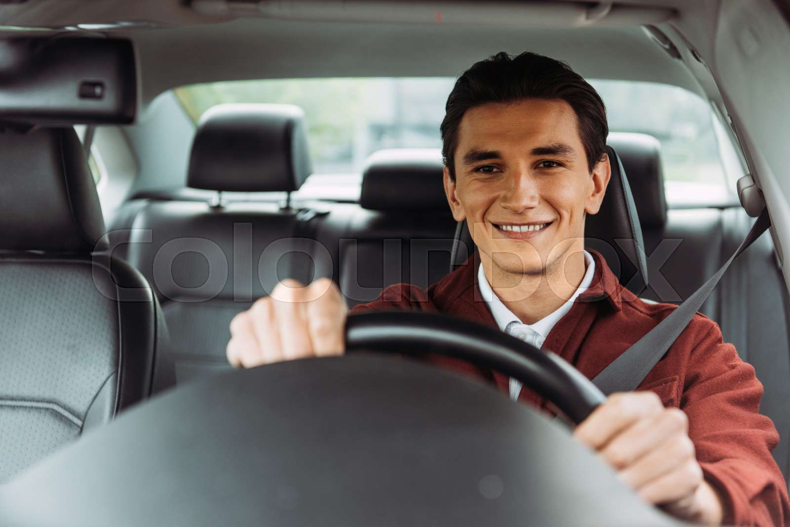 Smiling handsome man holding steering wheel of car | Stock image ...