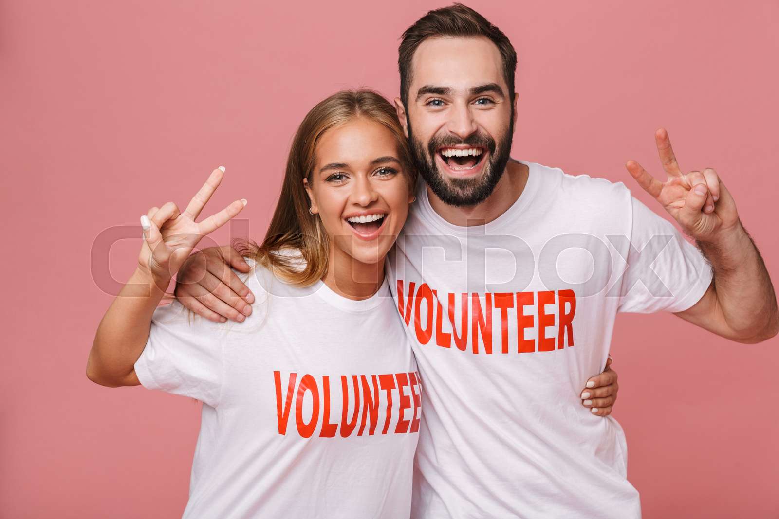 Image of young volunteers wearing uniform t-shirts showing peace sign ...