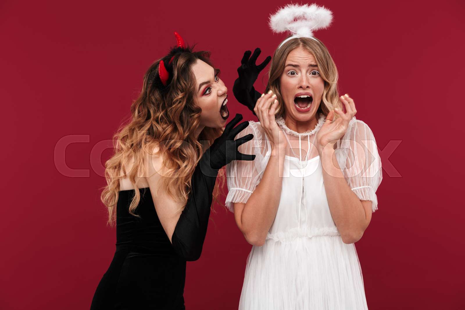 Demon near scared angel in carnival costumes | Stock image | Colourbox