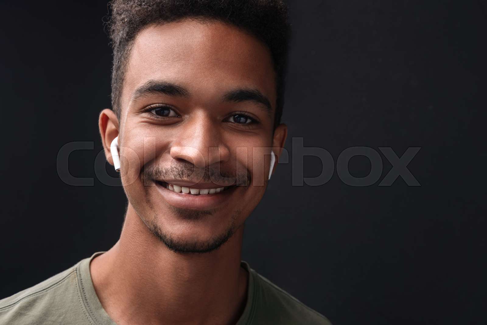 Image of smiling african american guy using earpods | Stock image ...