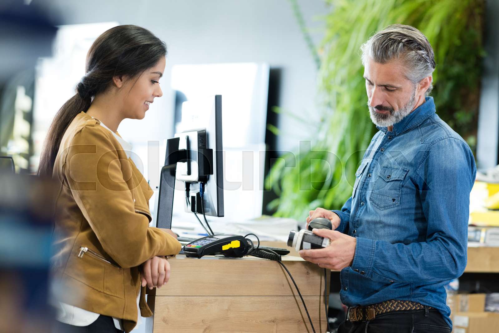 mature male sales assistant scanning product at counter | Stock image ...