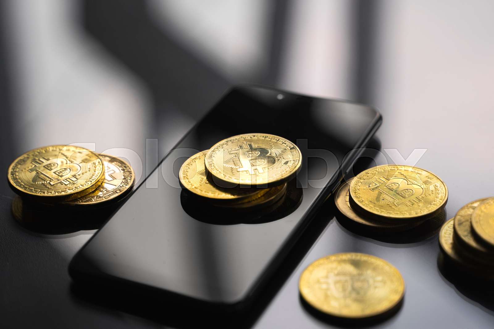 Golden bitcoin coin on a smartphone with a lot of bitcoins coins on a ...