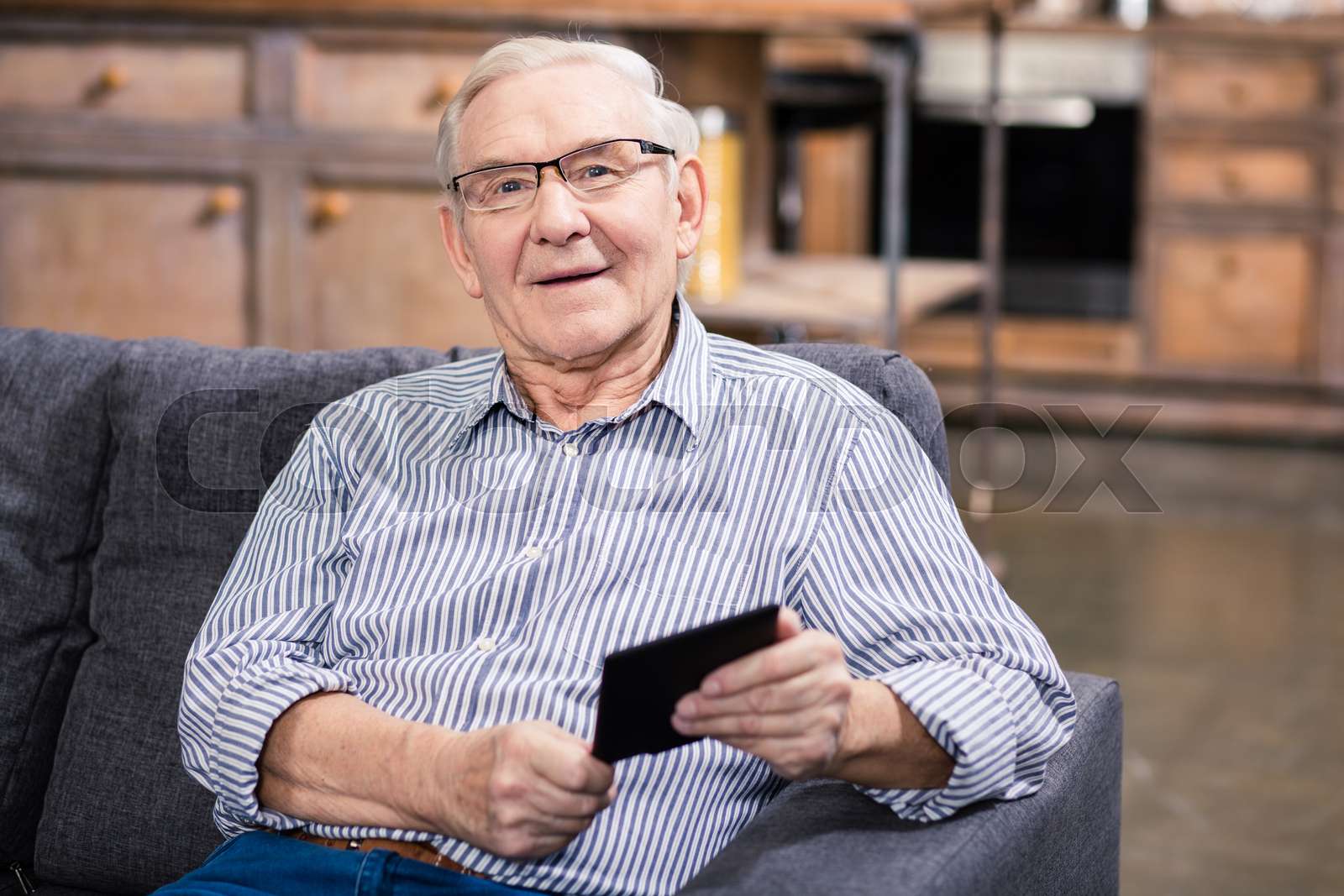 Smiling elderly man sitting on the couch | Stock image | Colourbox