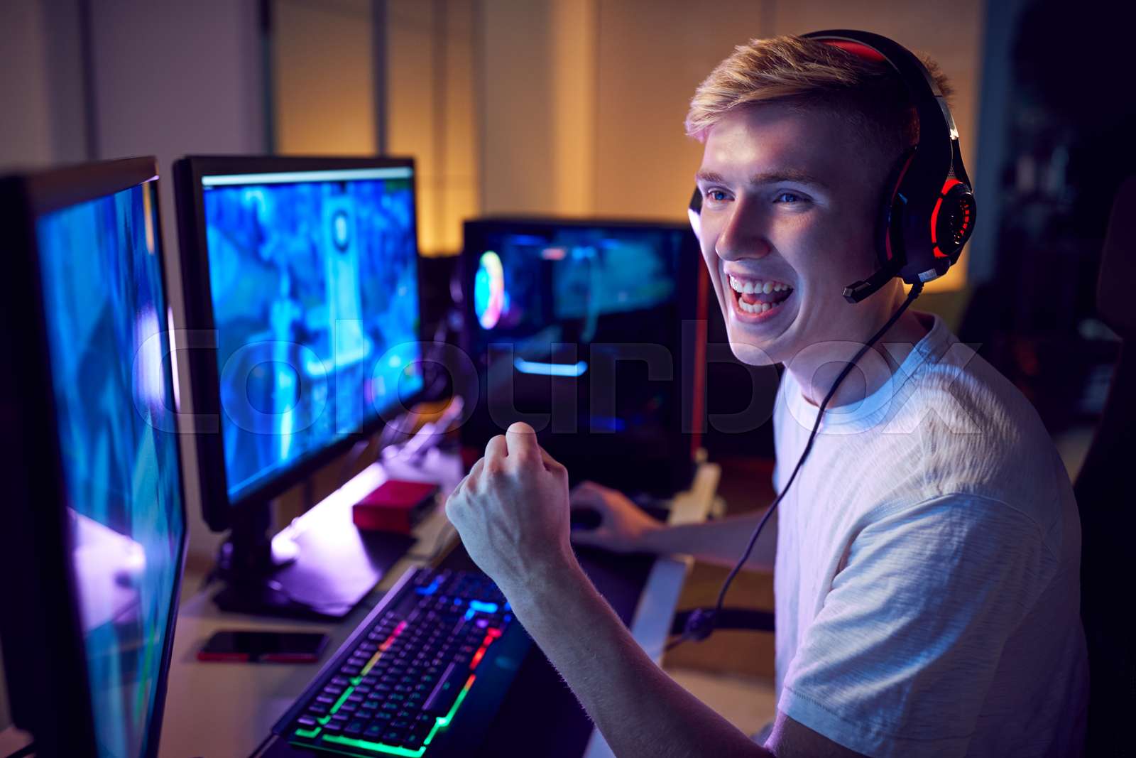 Teenage Boy Wearing Headset Gaming At Home Using Dual Computer Screens ...