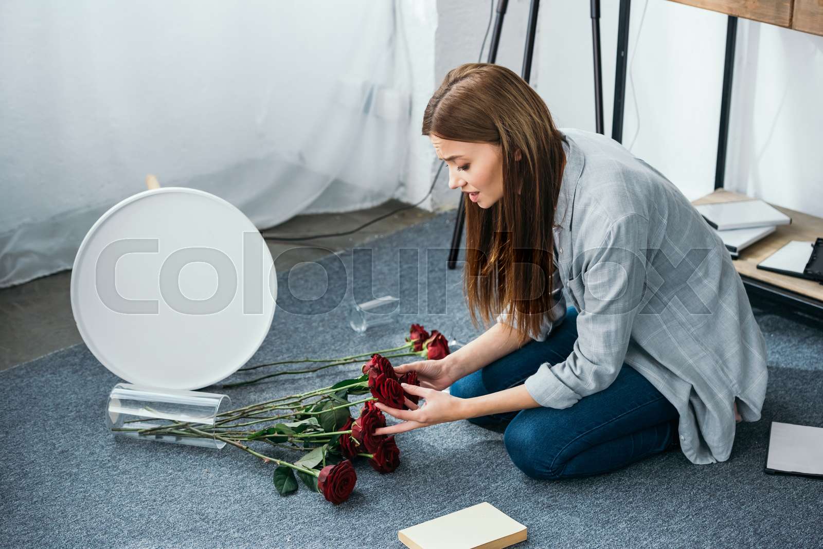 attractive and sad woman holding flowers in robbed apartment | Stock ...