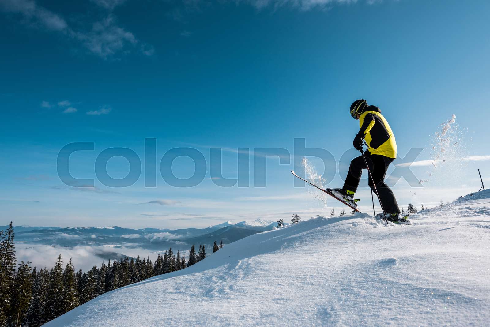 side view of skier holding ski sticks and making step against sky in ...