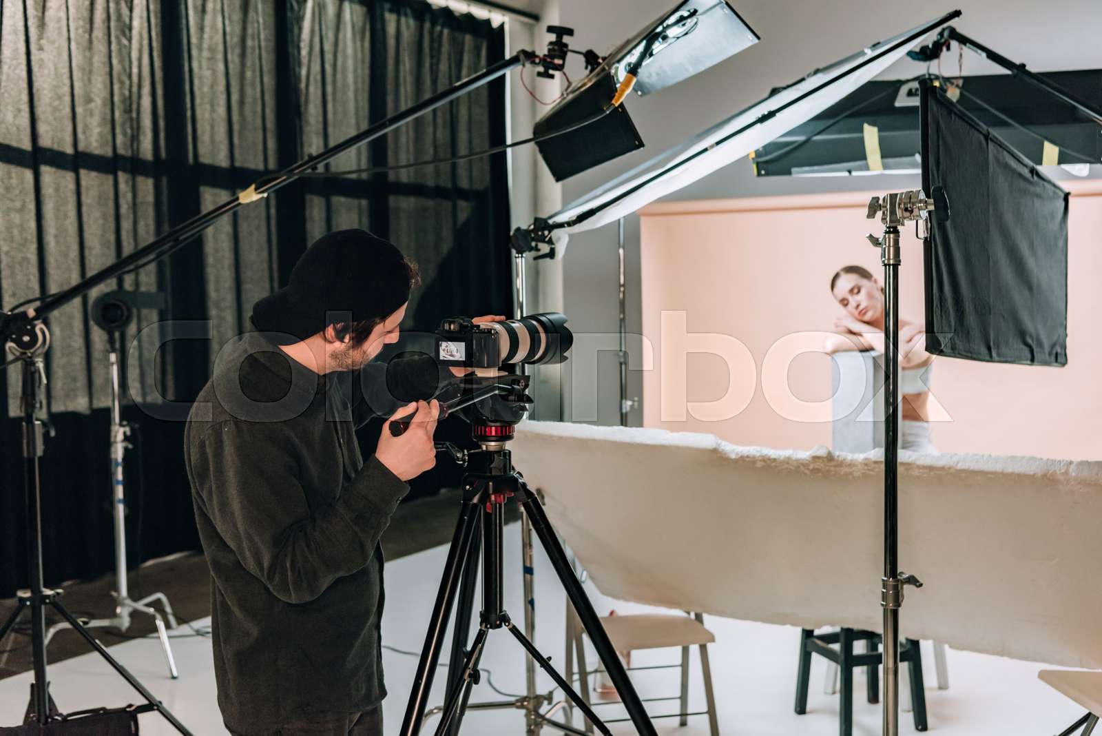 Cameraman shooting attractive model in photo studio with spotlights ...