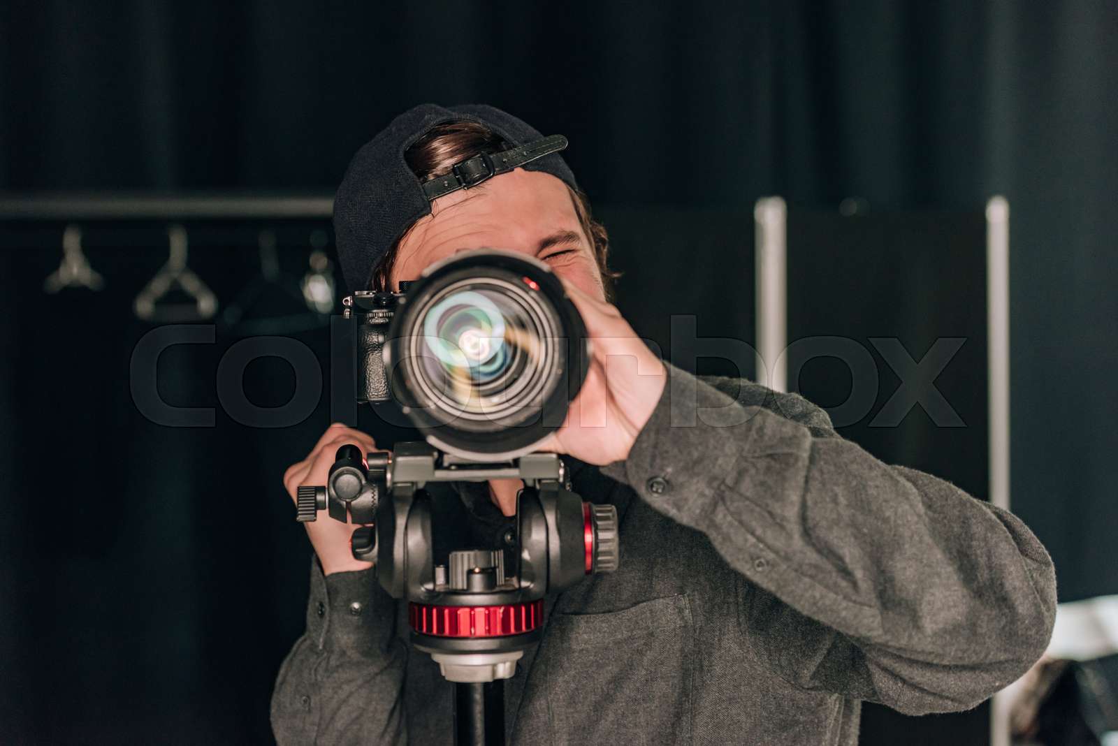 Videographer looking through camera while working in photo studio ...