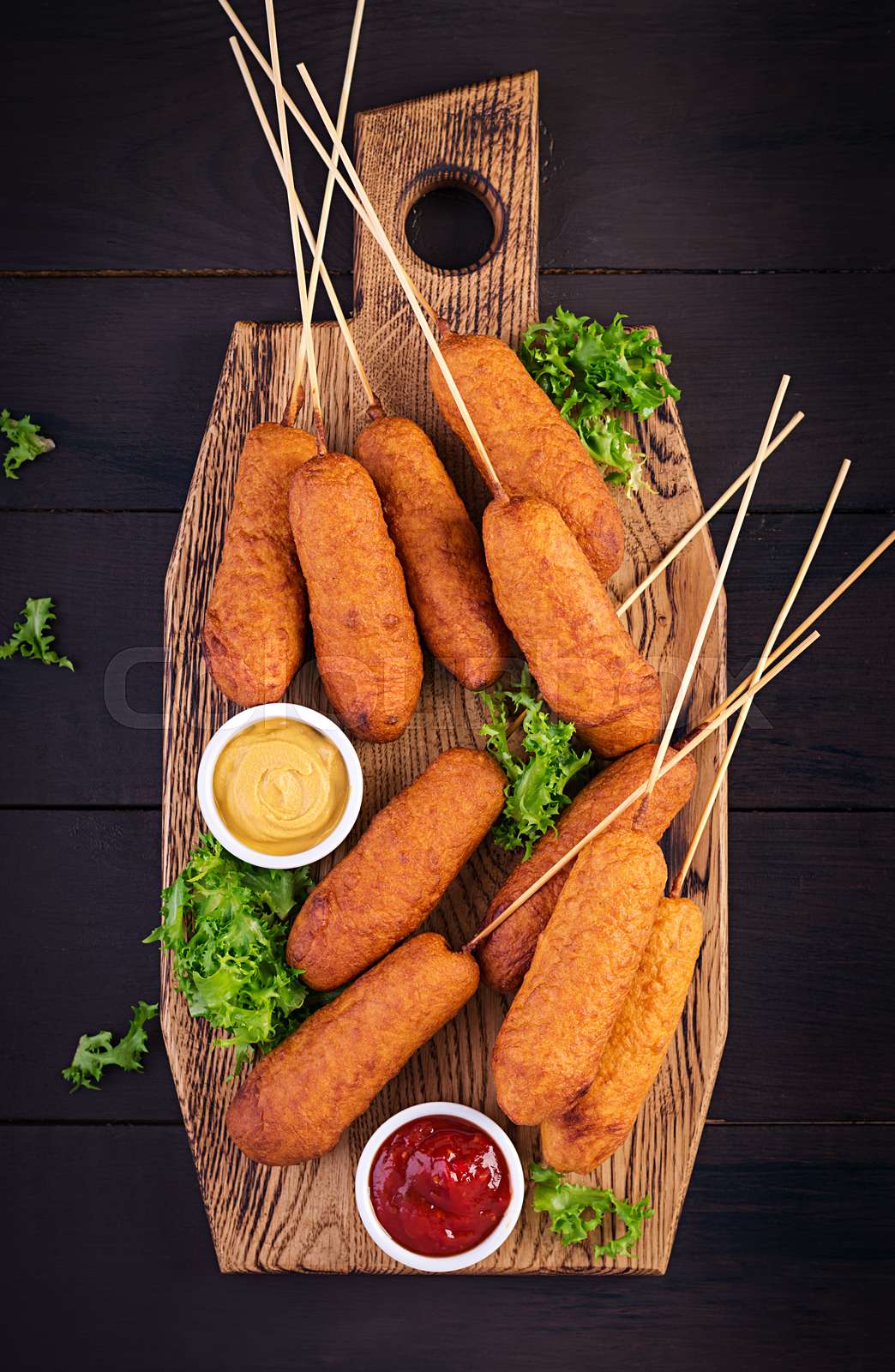 Traditional American corn dogs with mustard and ketchup on wooden board ...