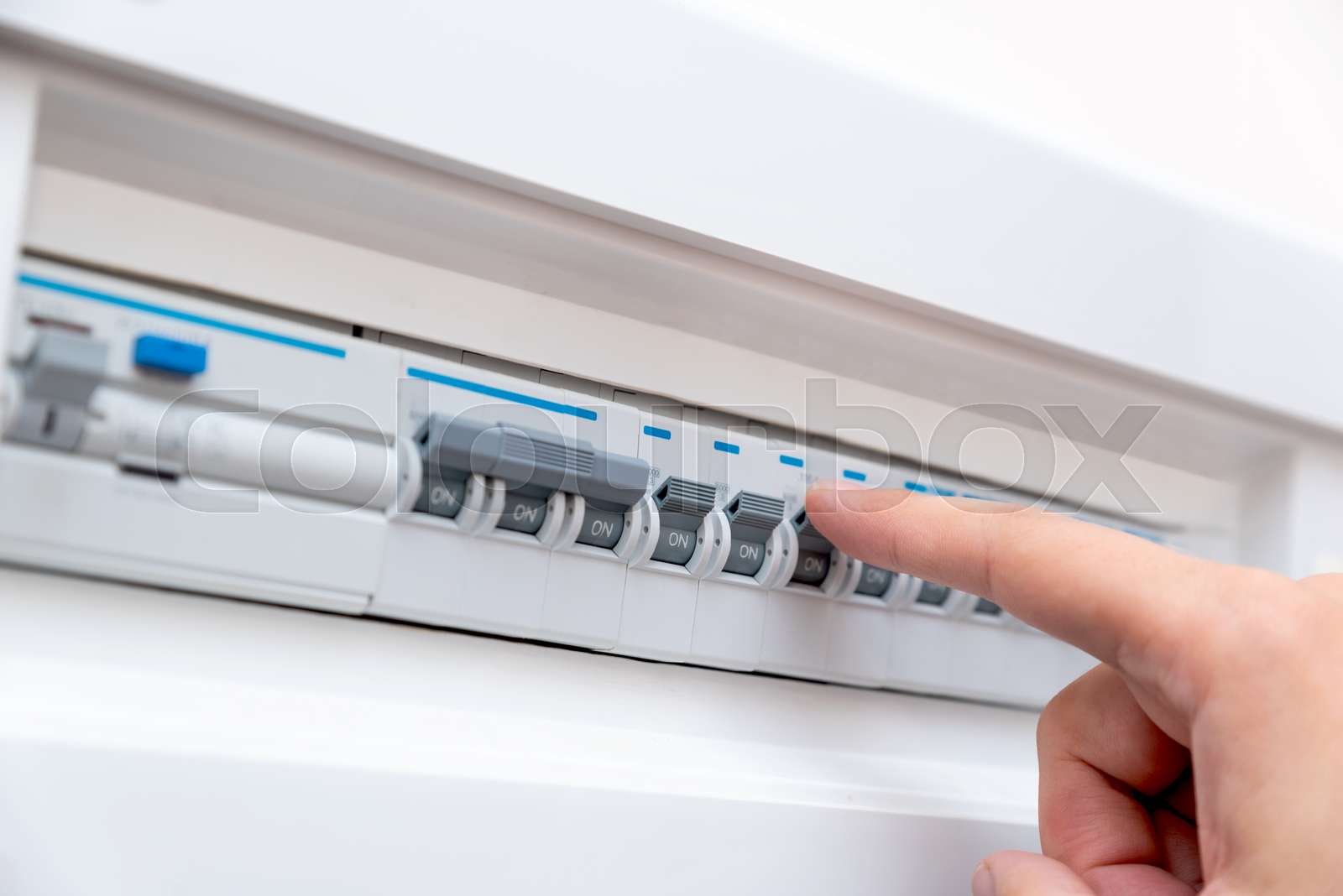 Man switches fuse in electrical switchboard | Stock image | Colourbox