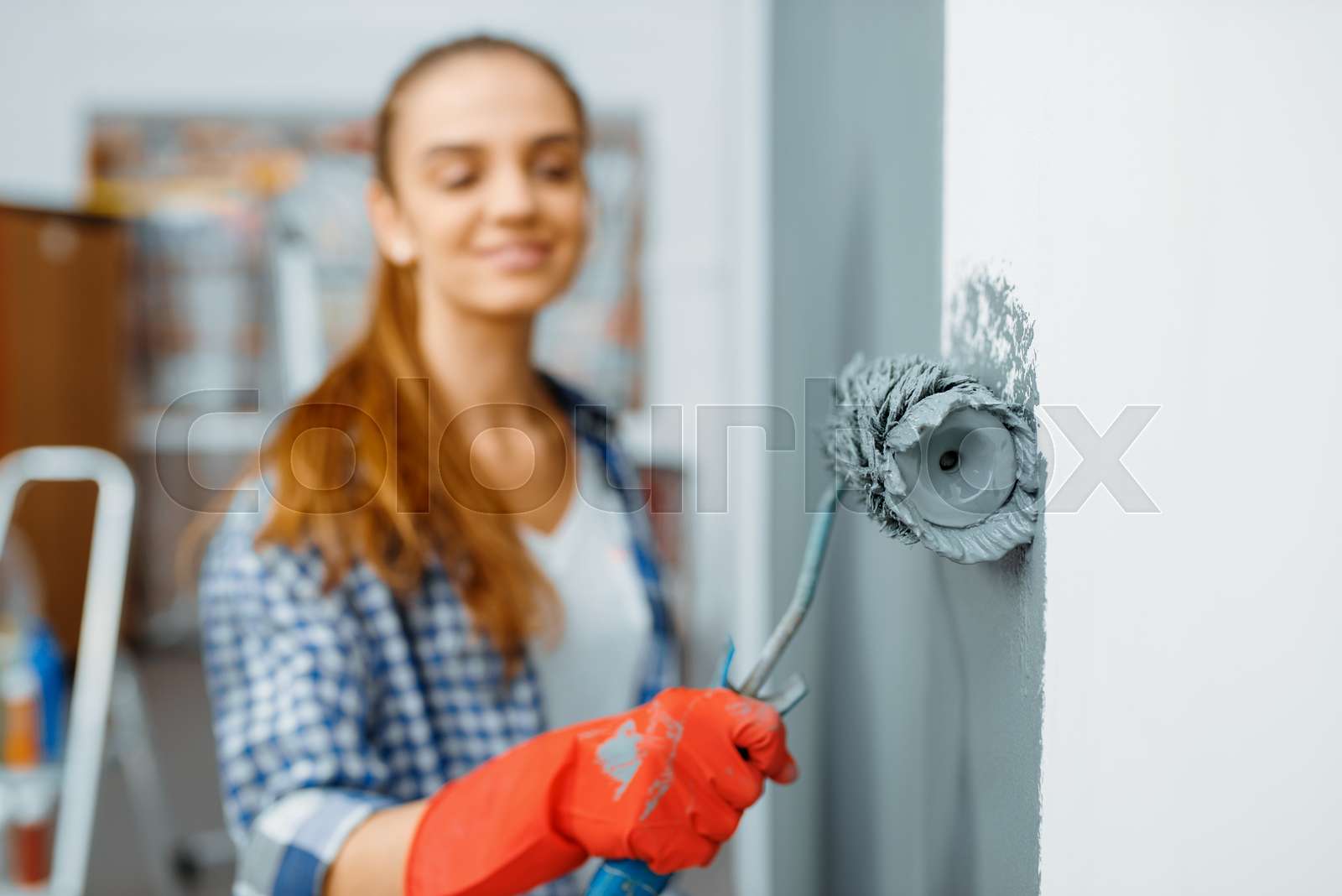 Female house painter in gloves paints the wall | Stock image | Colourbox
