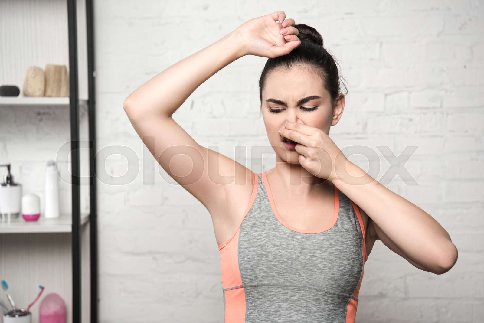 shocked woman plugging nose with hand while looking at underarm | Stock ...
