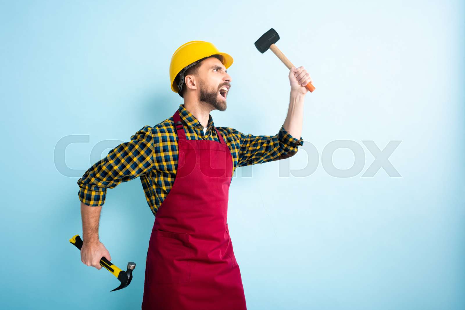 side view of angry workman holding hammers on blue | Stock image ...