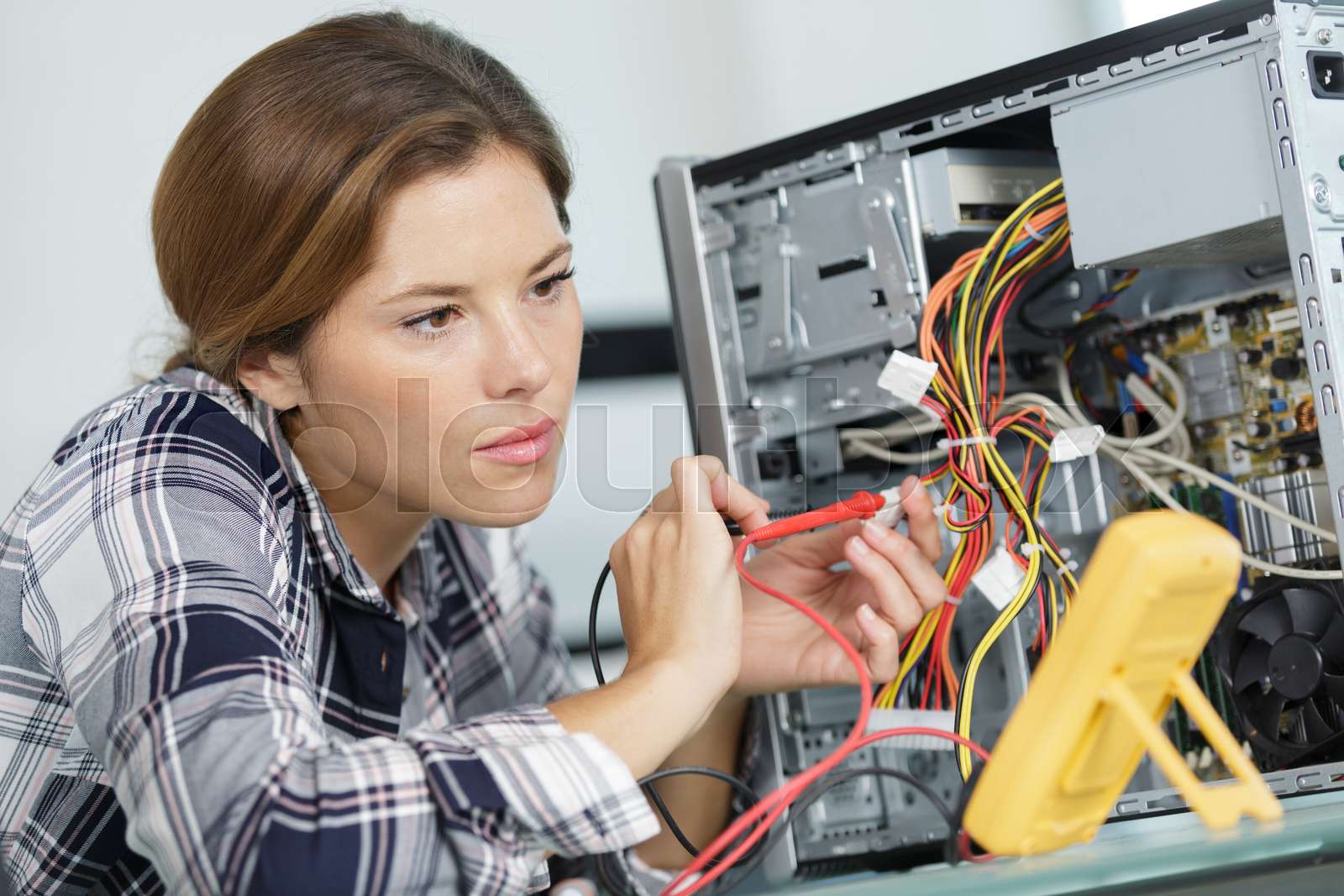 woman checking computer with a multimeter | Stock image | Colourbox