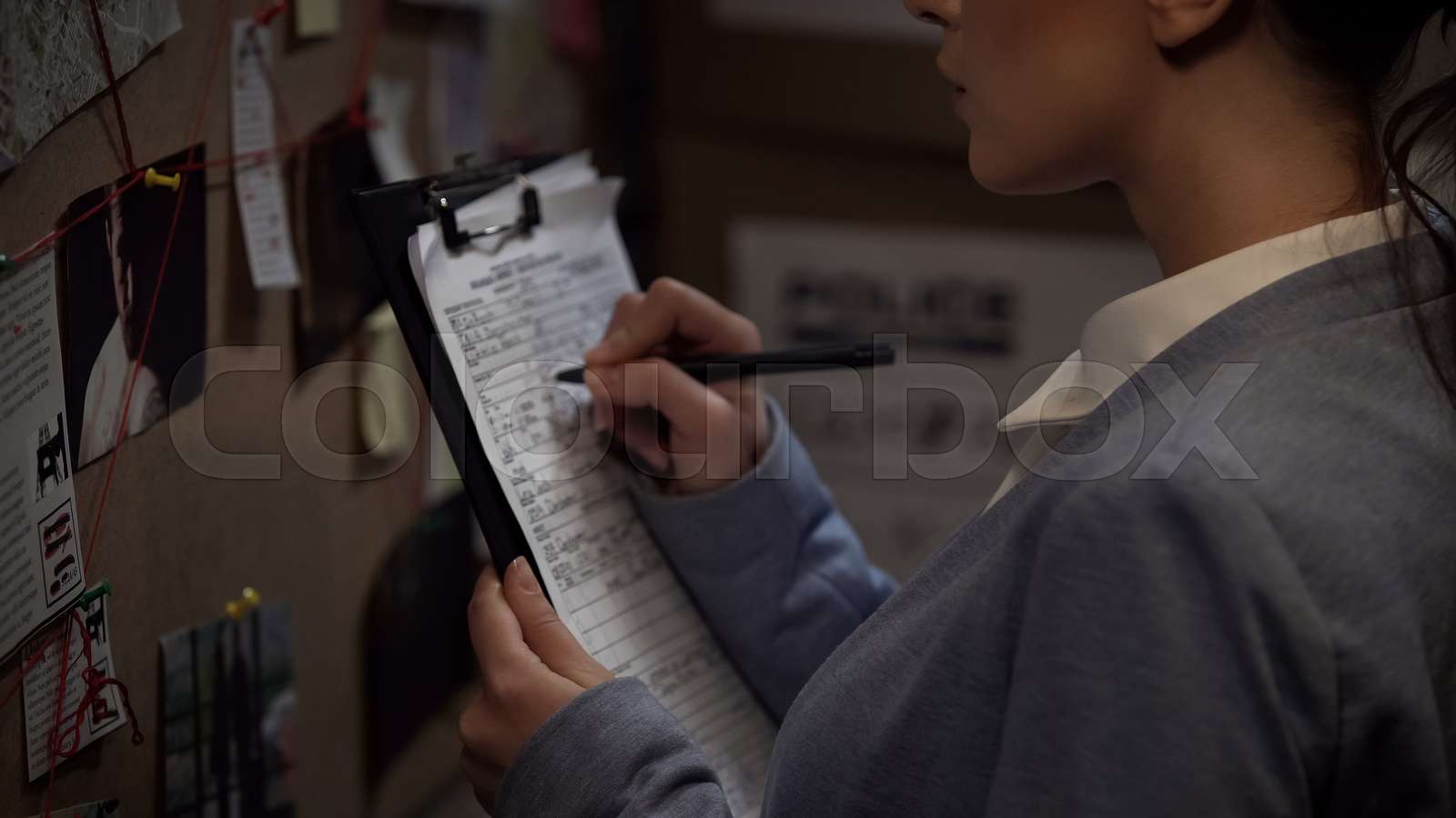 Criminal investigator drawing up record, writing down case details ...