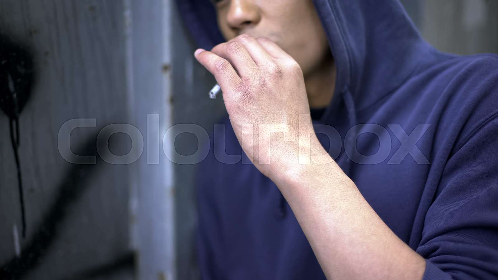 African american guy inhaling cigarette smoke, hiding from adults ...