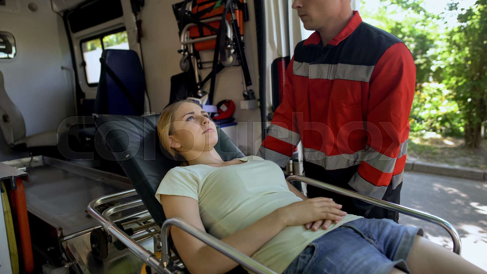 Paramedics carrying patient on stretcher into ambulance, fast qualified ...