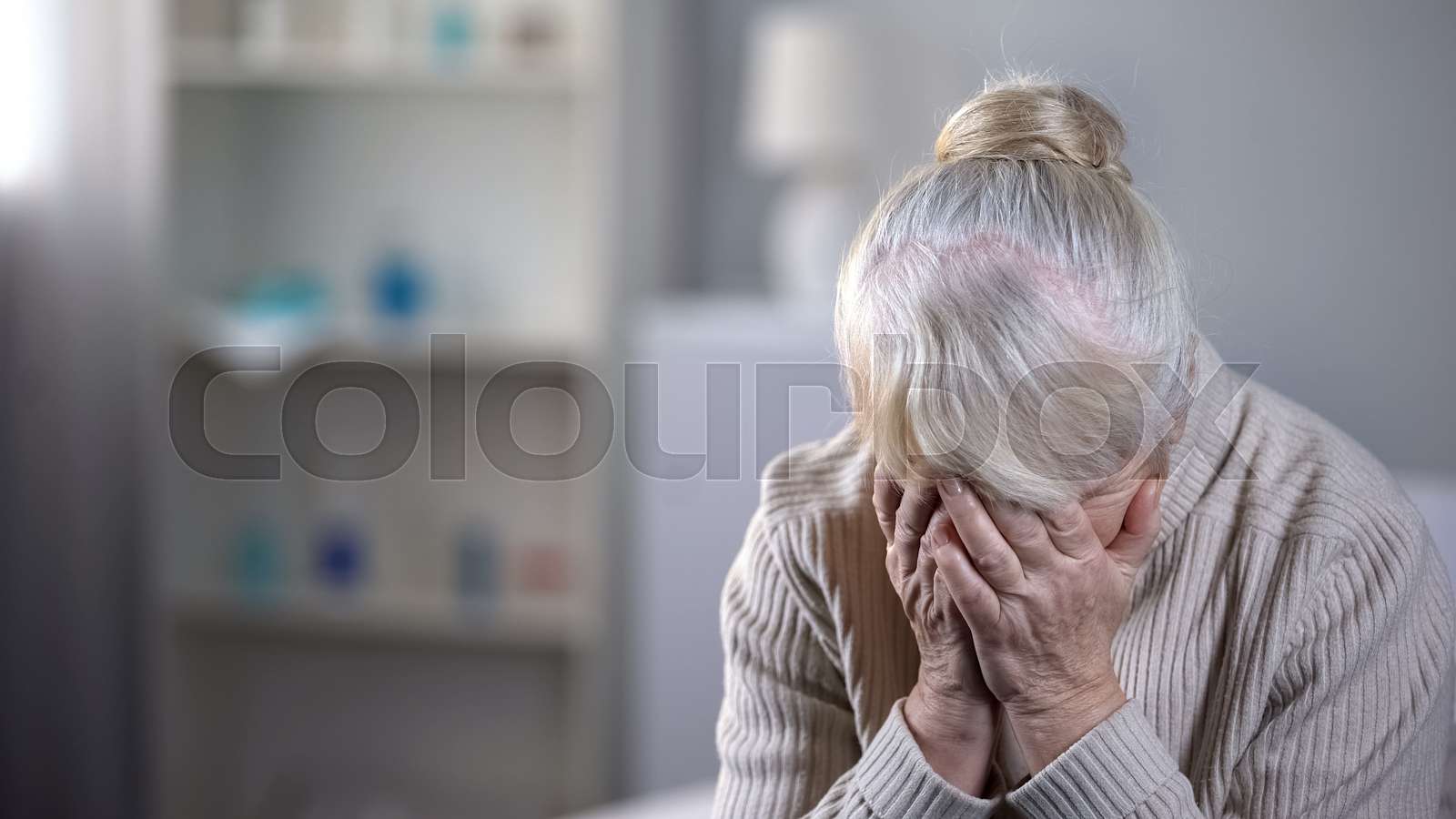 Unhappy elderly lady sitting alone in living room and deeply crying ...