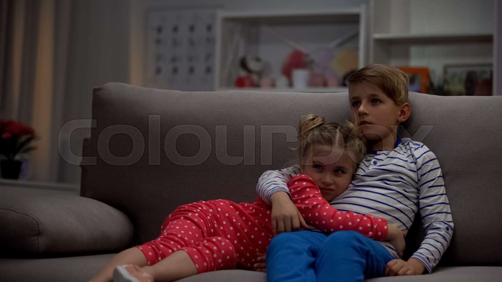 Brother embracing girl, watching horror movie, protecting sister from ...