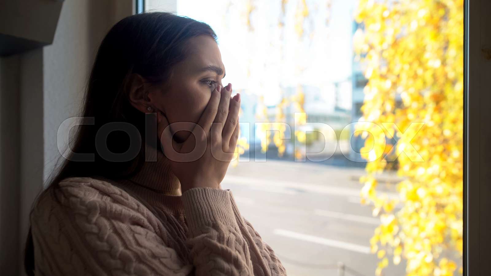 Crying lady looking through window, afraid of going outdoors ...
