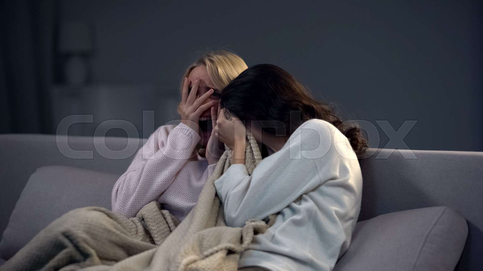 Two beautiful scared girls watching horror movie at night, frightening ...
