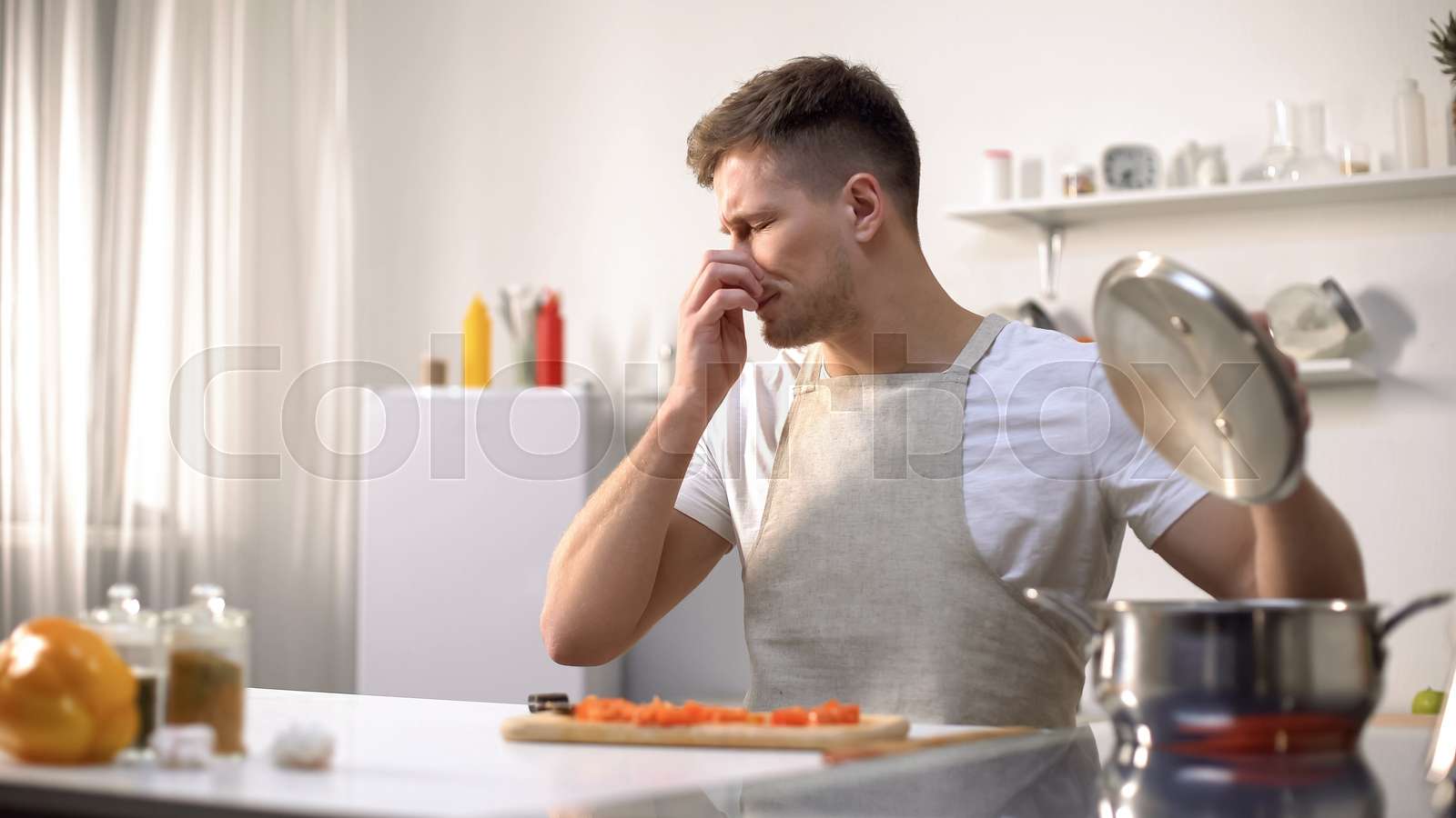 Young man disgusted with stinky meal on stove, spoiled ingredients ...