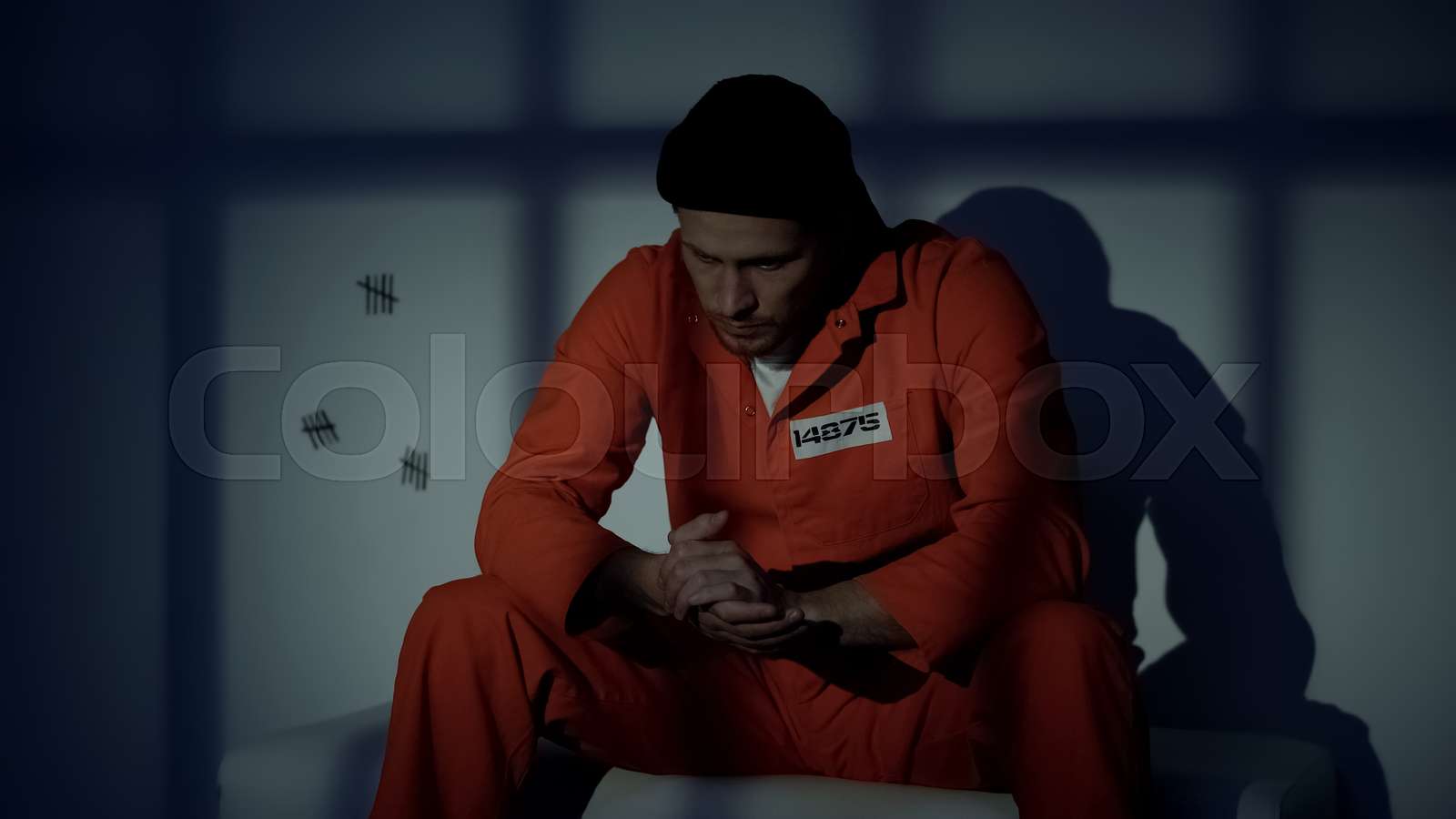Unhappy Caucasian male prisoner feeling guilty about crime, thinking in ...