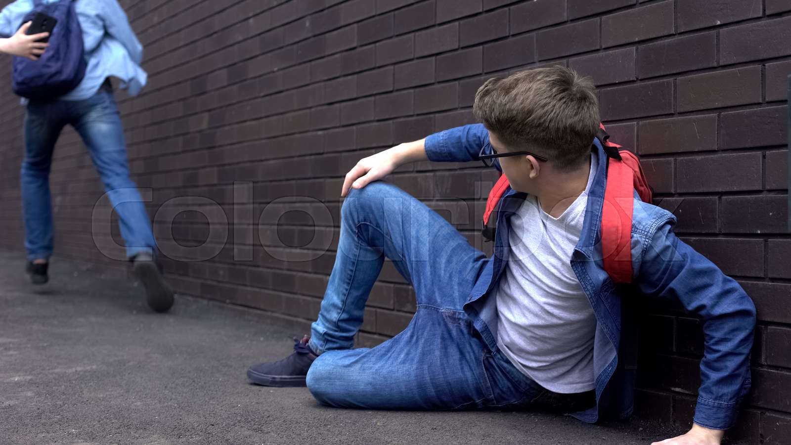 Punched boy lying looking at hooligan running away, bullying and theft ...