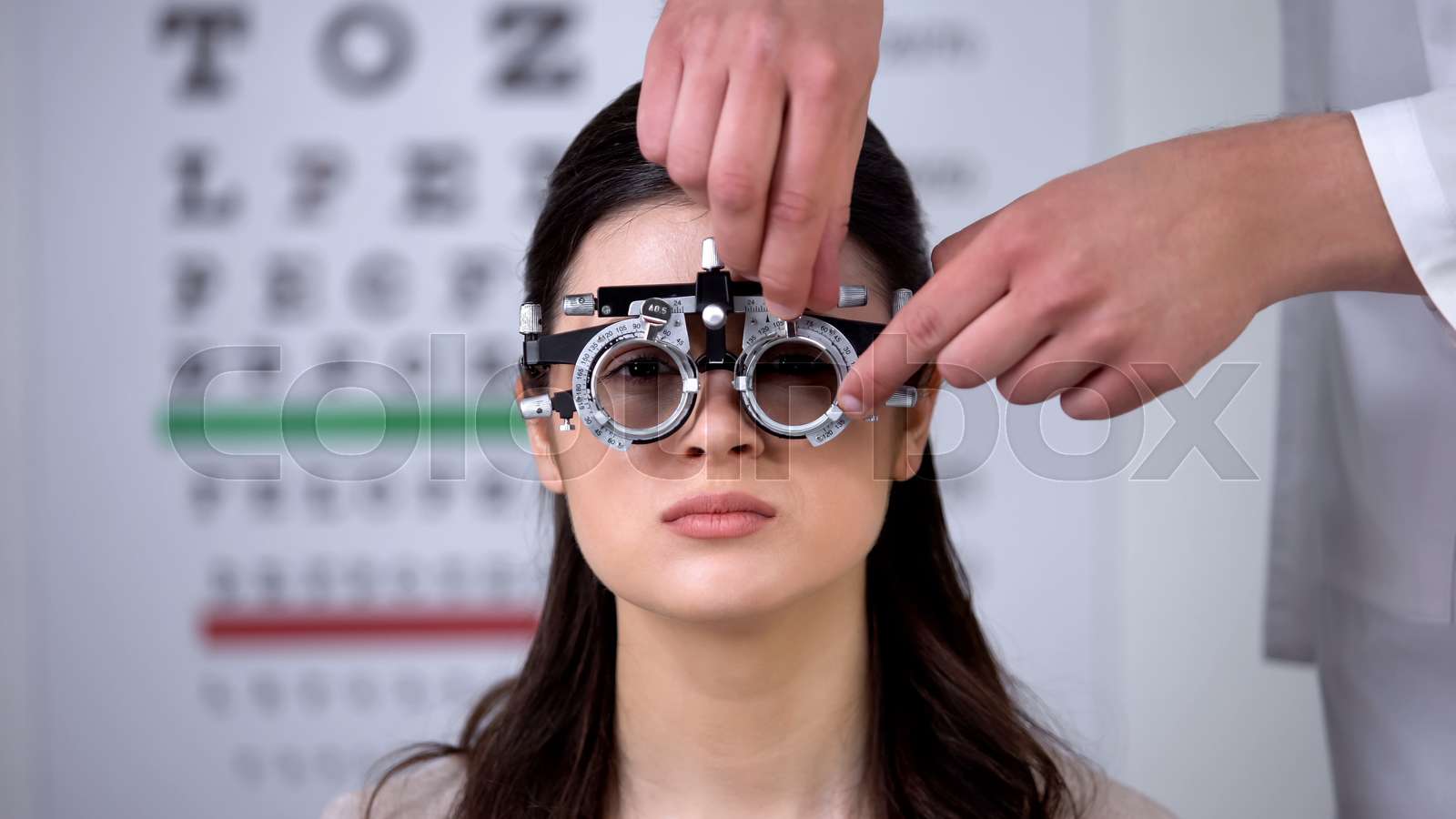 Doctor choosing lenses for patient in optical trial frame, lady shaking ...