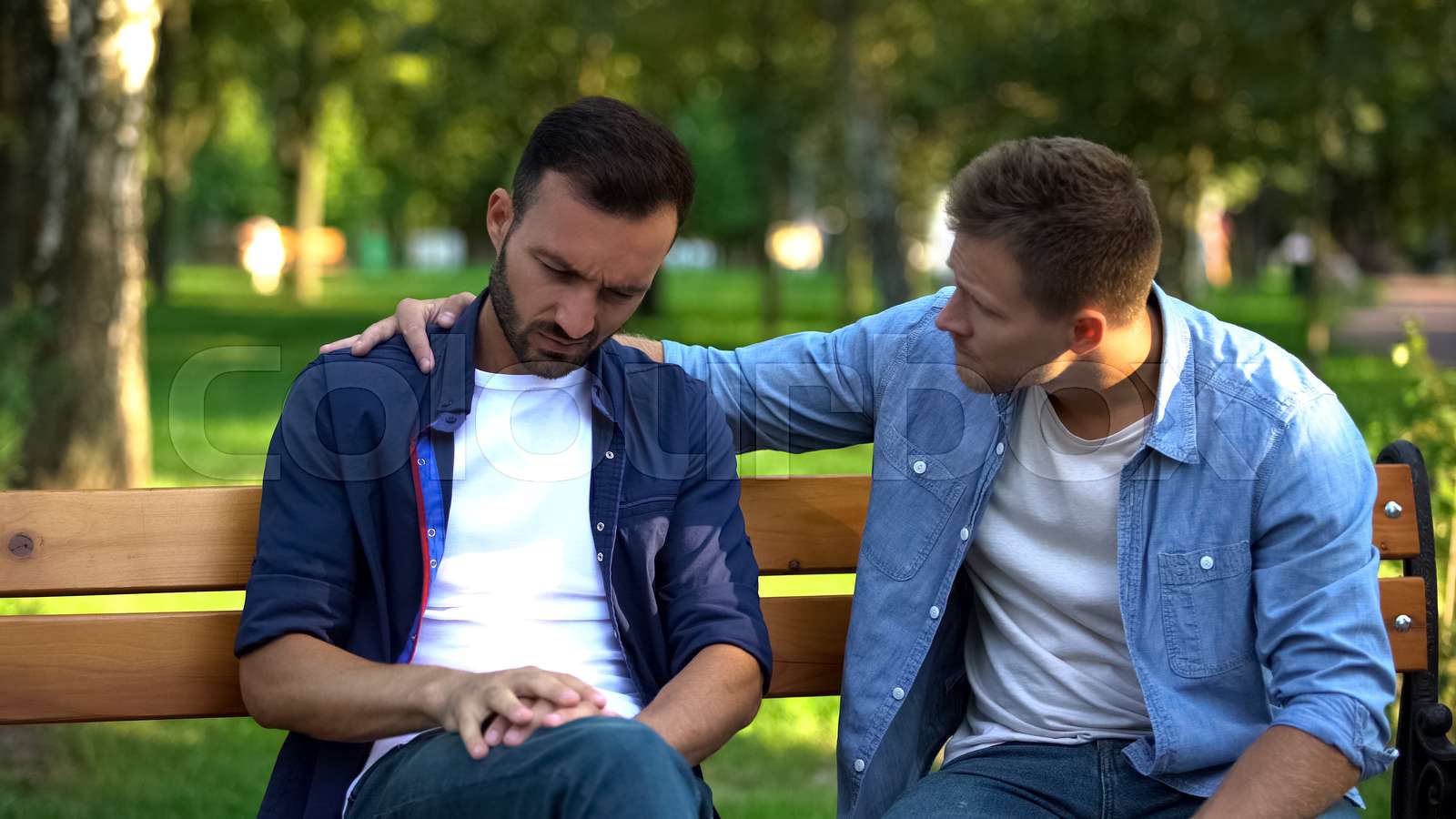 Young male supporting friend sitting outdoors together, friendship care ...